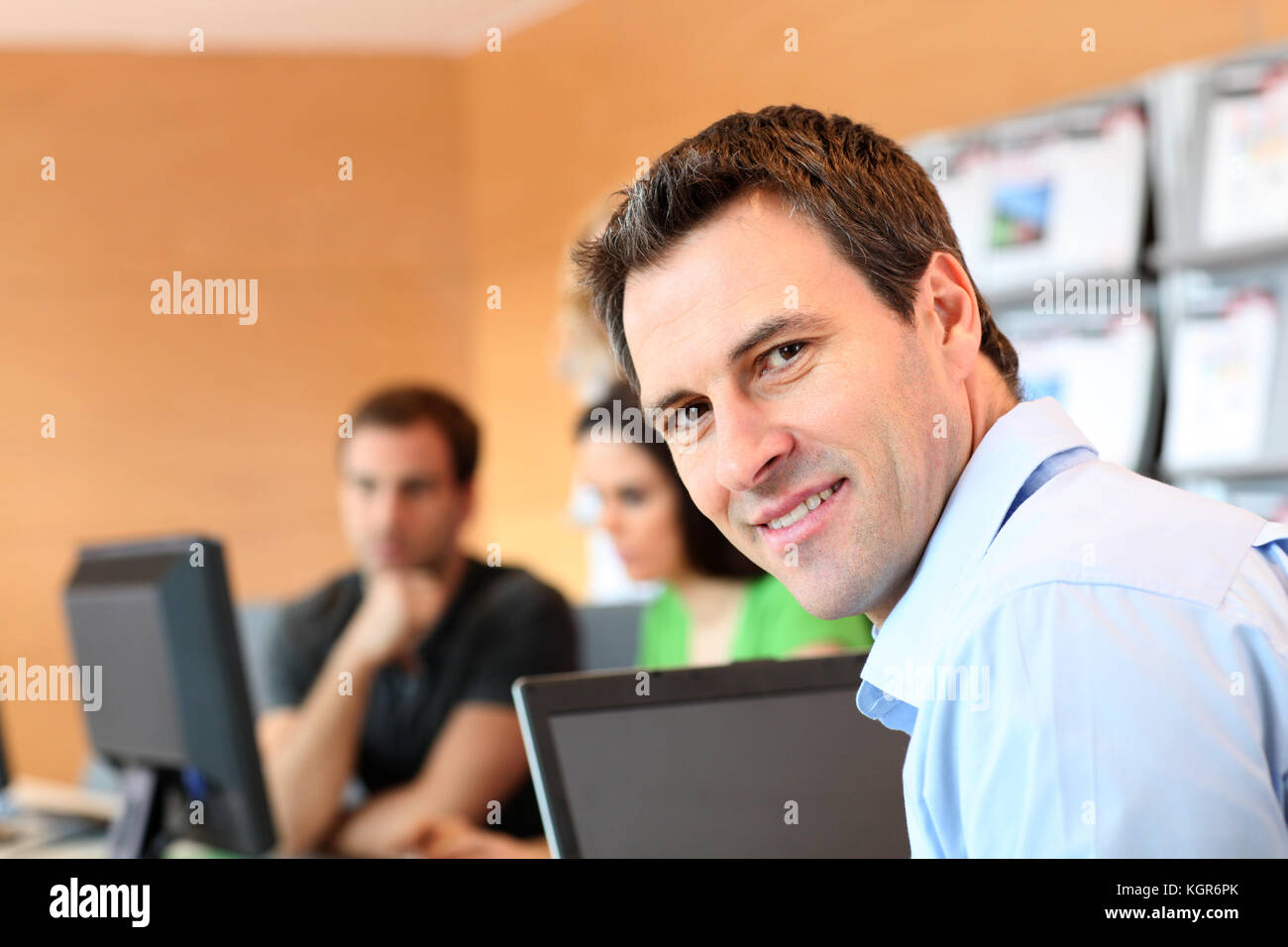 Man sitting in office in front of laptop computer Stock Photo - Alamy