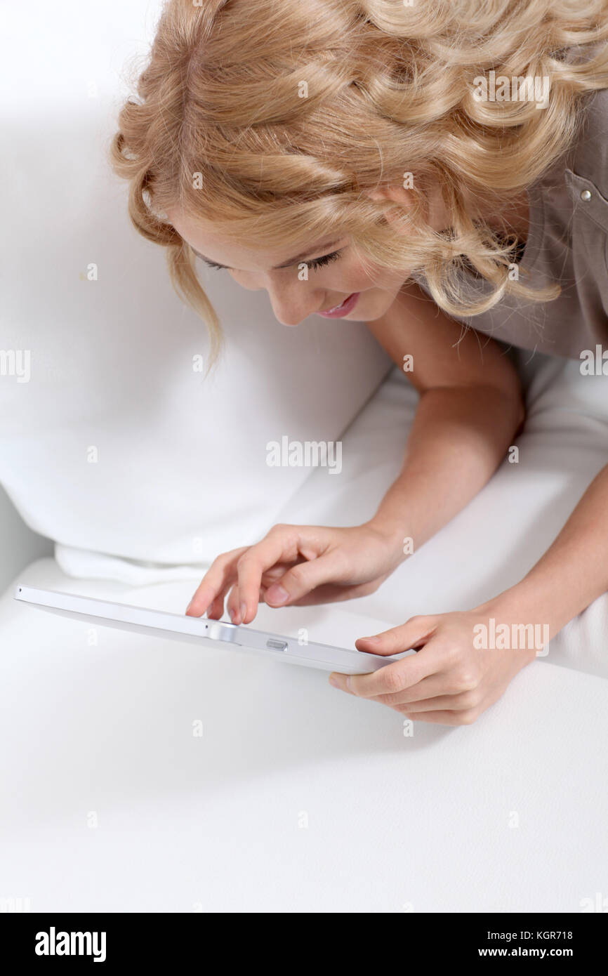 Smiling blond woman at home using electronic tablet Stock Photo - Alamy