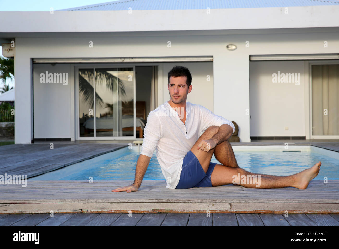 Young man doing stretching exercises on pool deck Stock Photo - Alamy