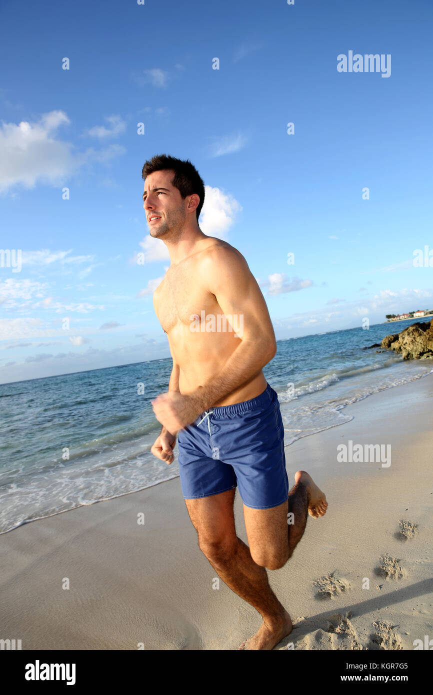 Young man running on the beach Stock Photo - Alamy