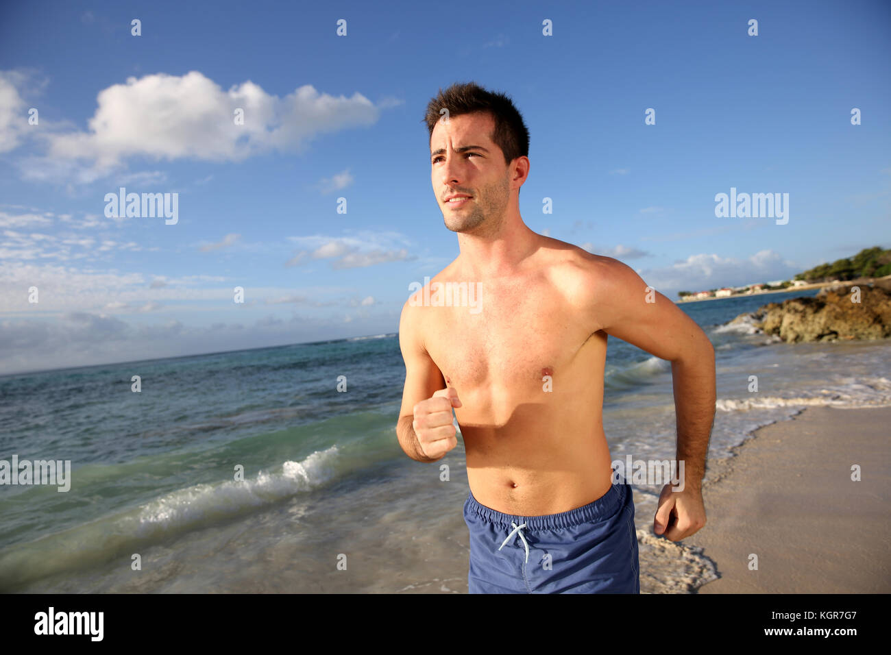 Young man running on the beach Stock Photo - Alamy