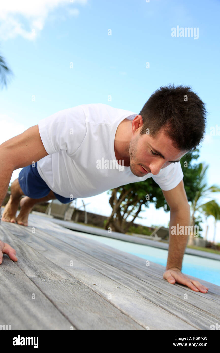 Young man doing pushups on pool deck Stock Photo - Alamy