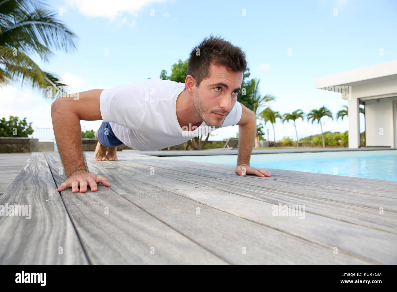 Young man doing pushups on pool deck Stock Photo - Alamy