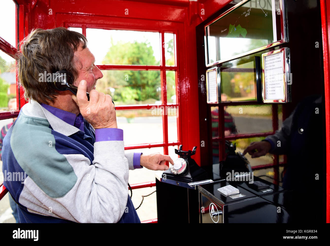 Male local resident using a traditional red phone box which has been ...
