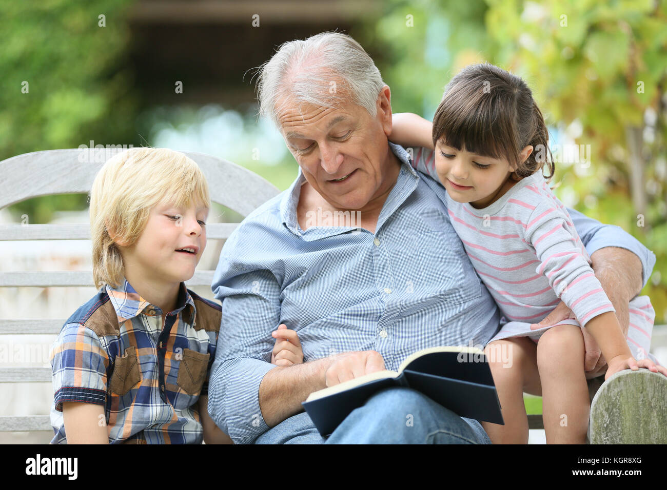 Senior man reading book with grandkids Stock Photo - Alamy