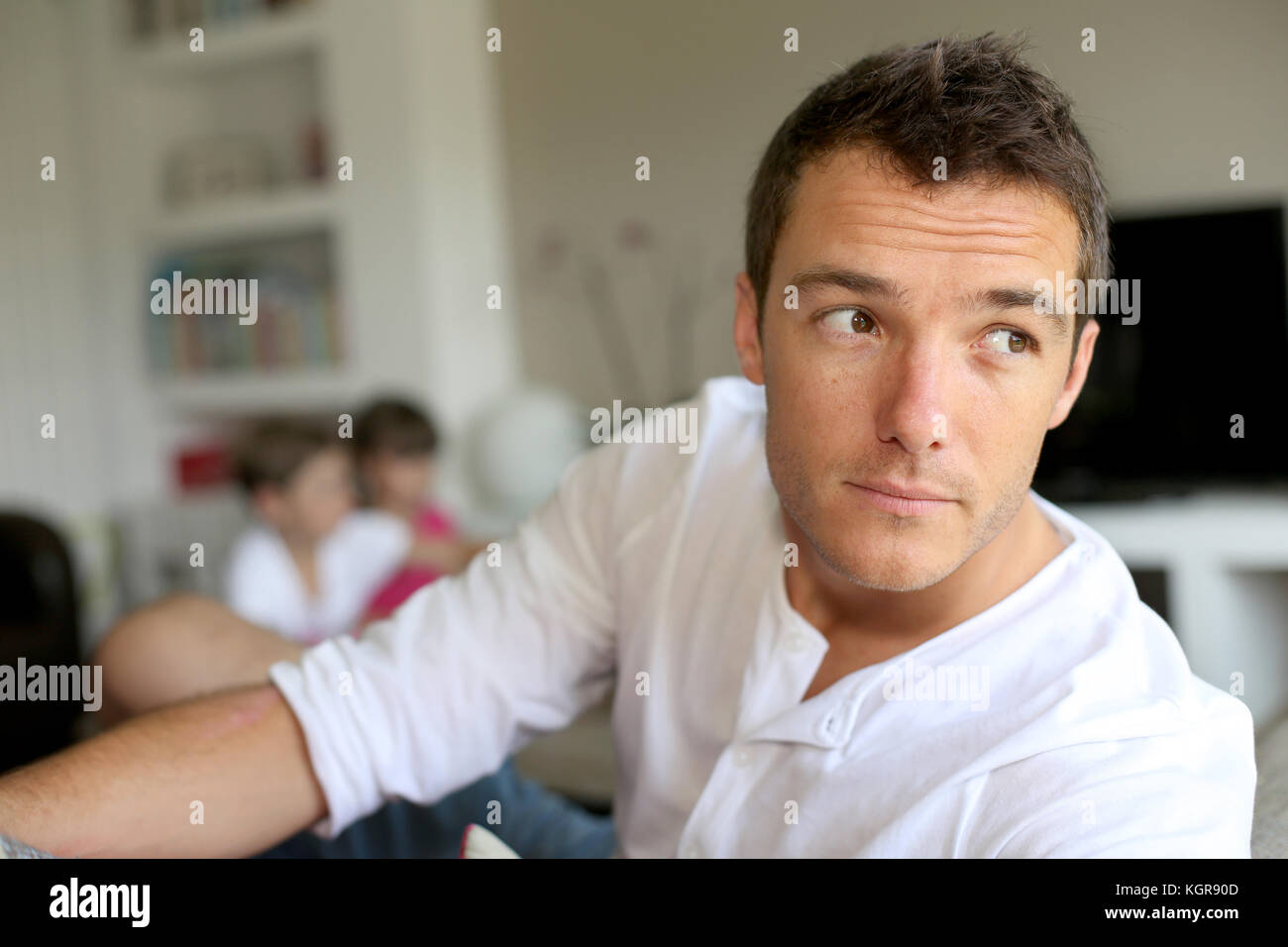 Portrait of man sitting in sofa, kids in background Stock Photo - Alamy