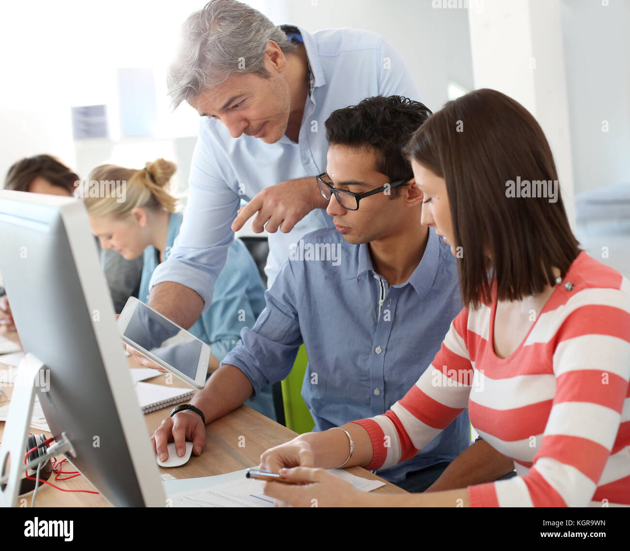 Teacher with group of students in class Stock Photo - Alamy