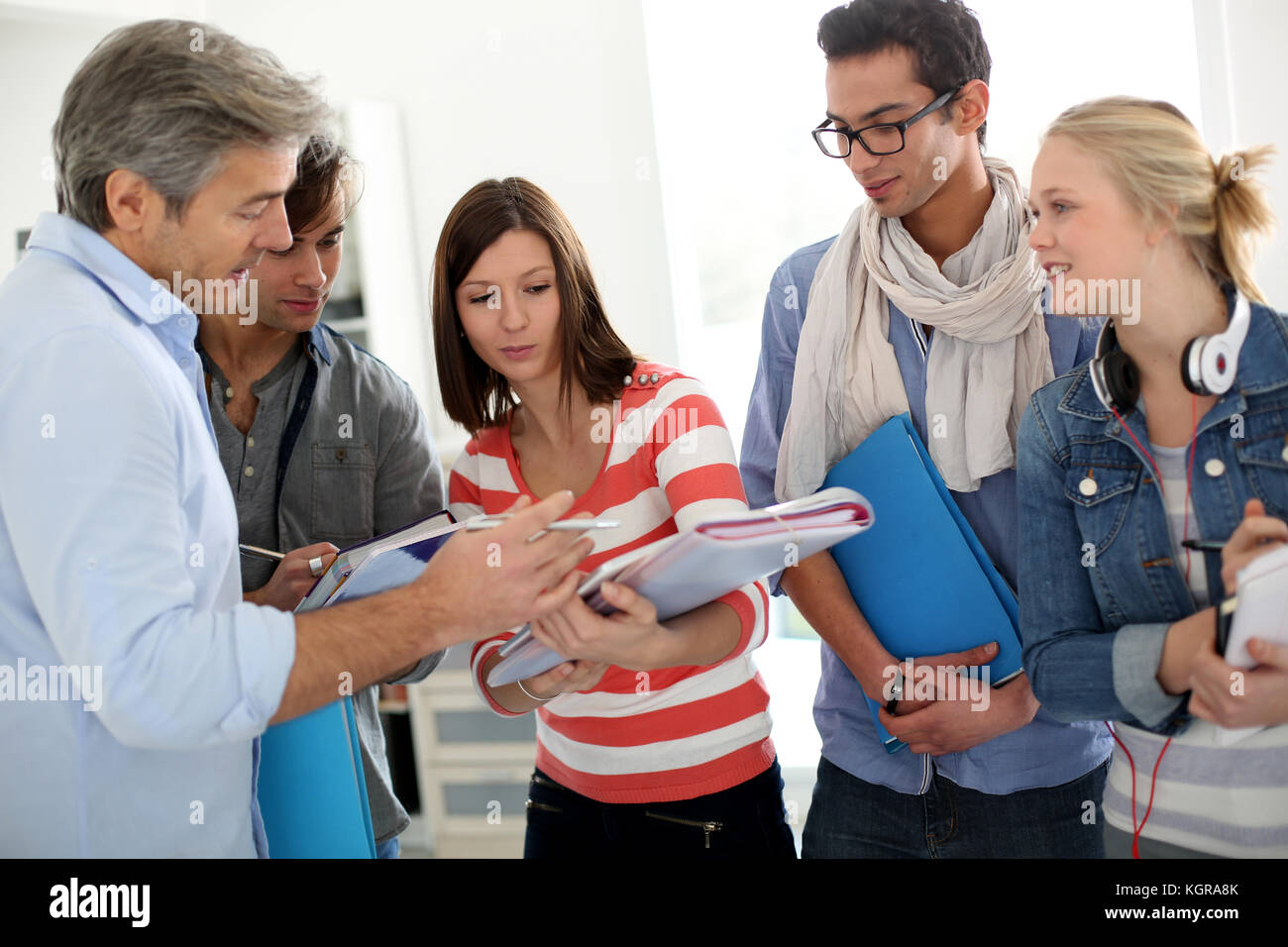 Students in school hallway asking questions to teacher Stock Photo - Alamy