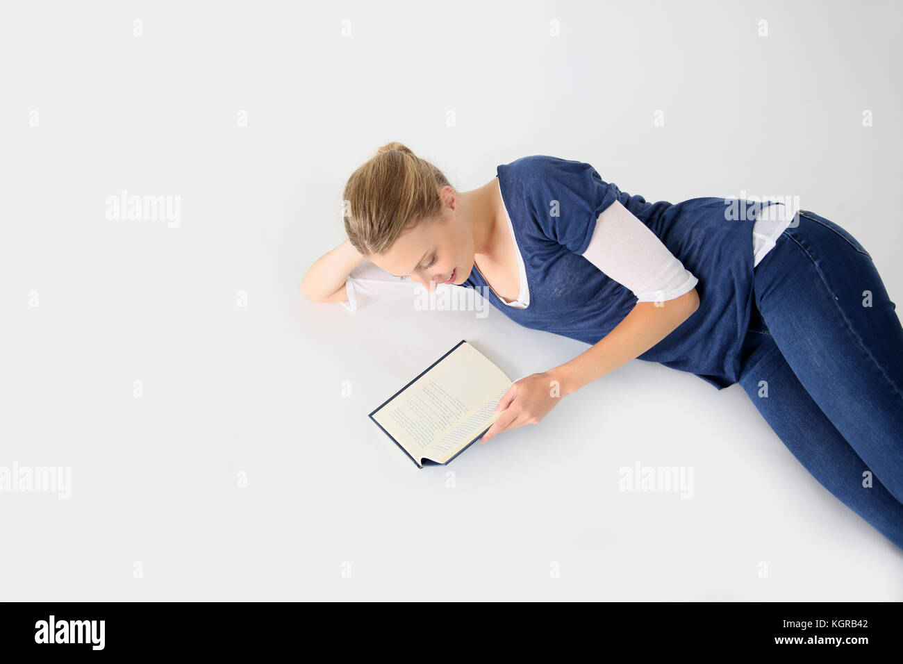 Young woman laying on floor reading a book, isolated Stock Photo - Alamy