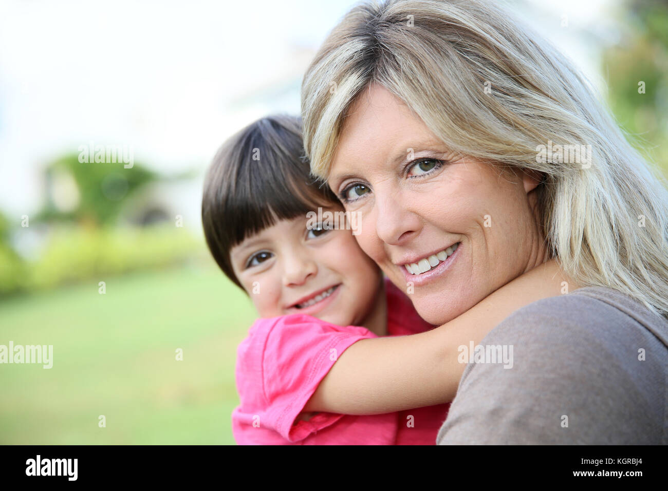 Cheerful woman embracing little girl in arms Stock Photo - Alamy