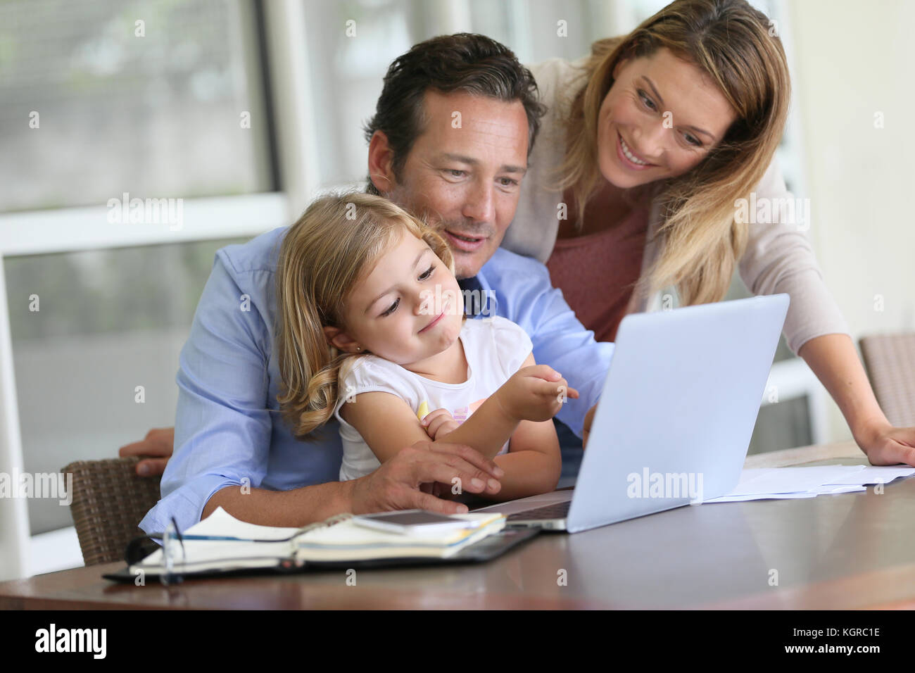 Parents with little girl looking at pictures on computer Stock Photo ...