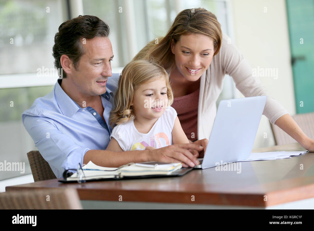 Parents with little girl looking at pictures on computer Stock Photo ...