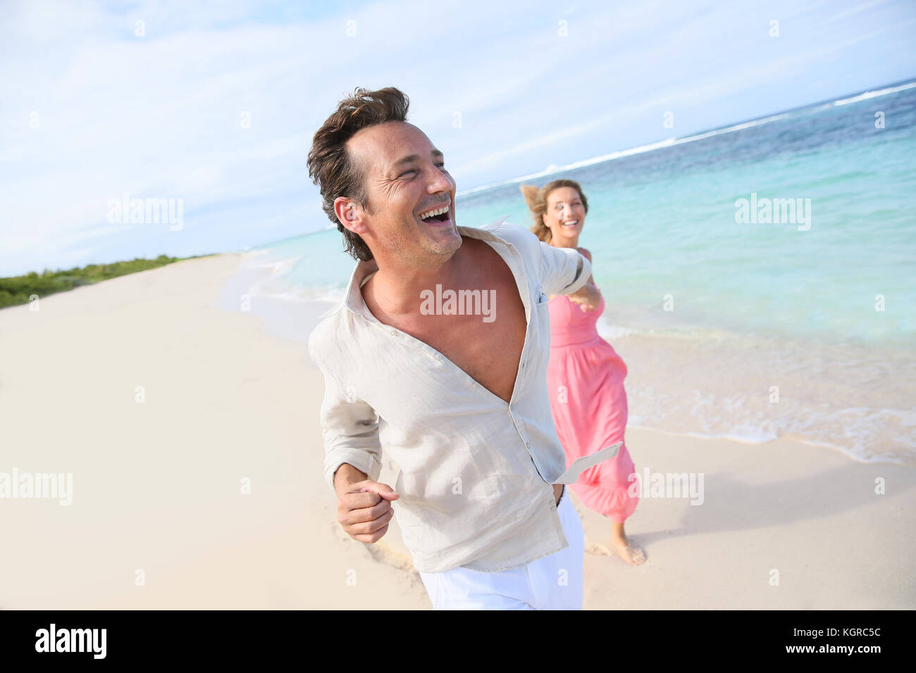Couple having fun running on a caribbean beach Stock Photo - Alamy