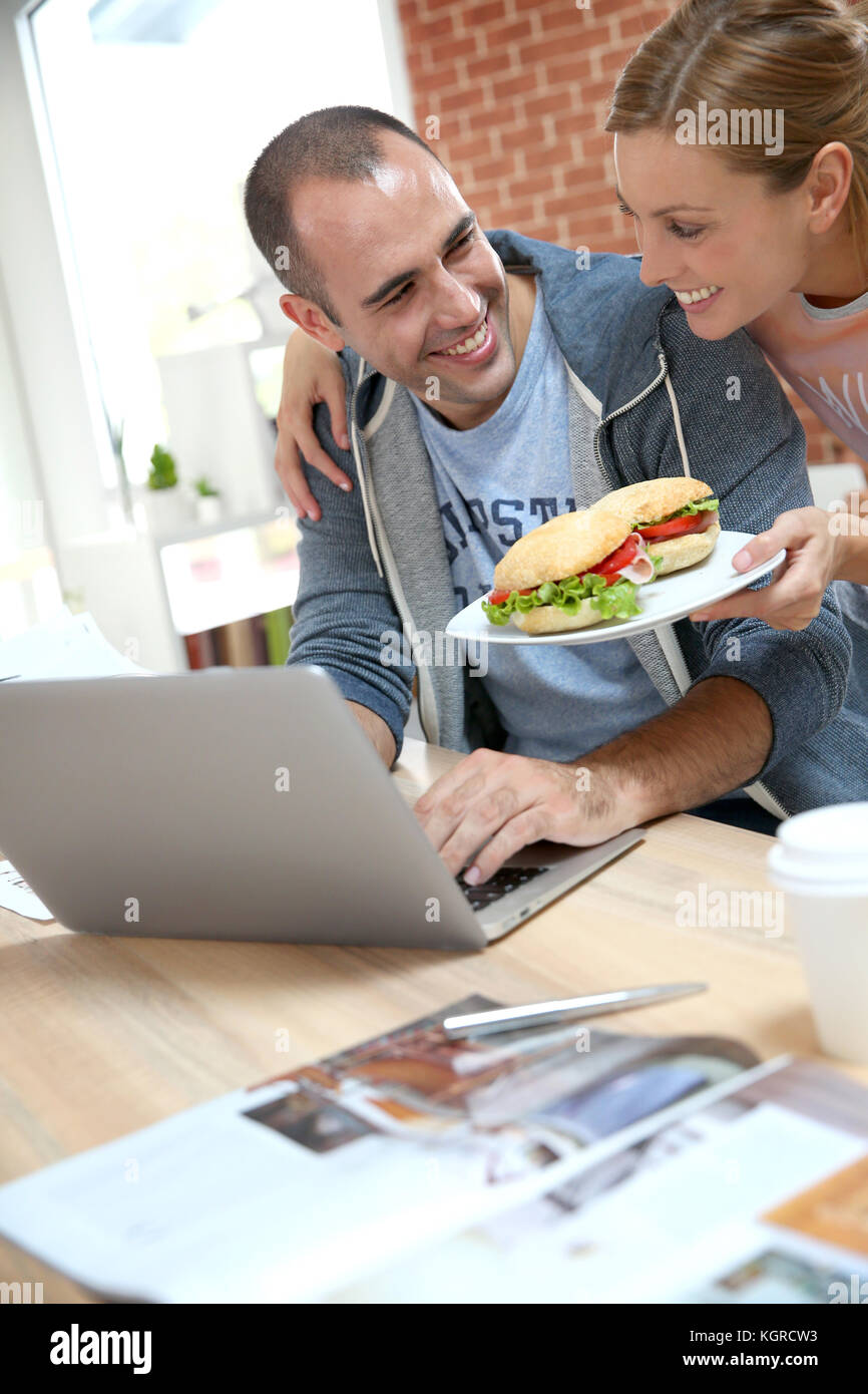 Roommates eating sandwich in front of laptop Stock Photo - Alamy