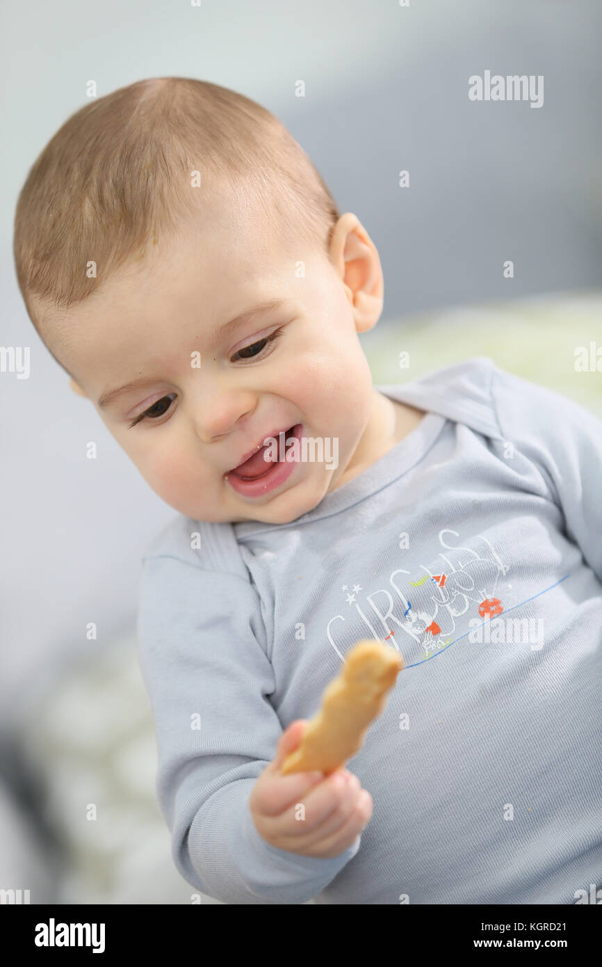 Portrait of cute baby boy eating child biscuit Stock Photo - Alamy