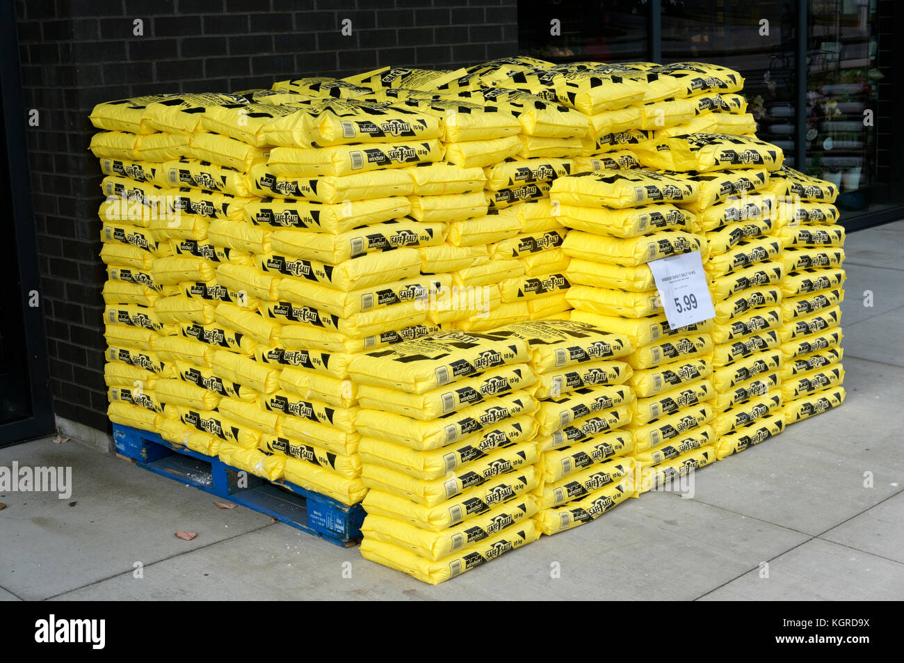 Yellow plastic bags of winter safety salt ice melt piled outside a ...