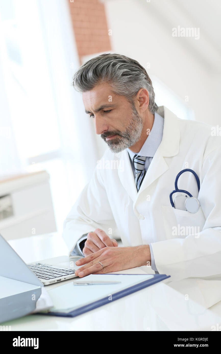 Doctor working in office on laptop Stock Photo - Alamy