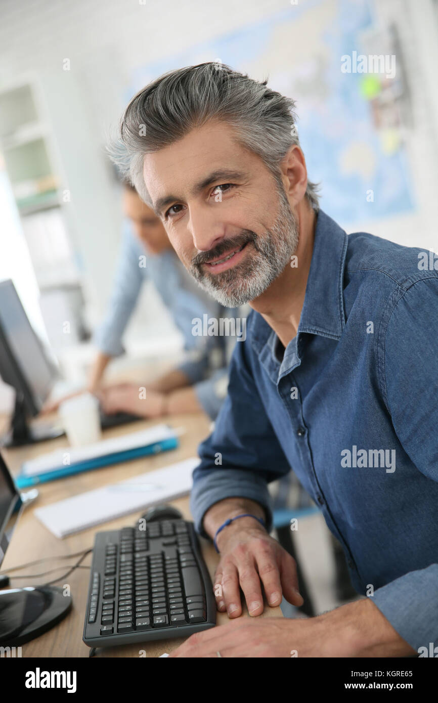 Smiling teacher working on desktop computer Stock Photo - Alamy
