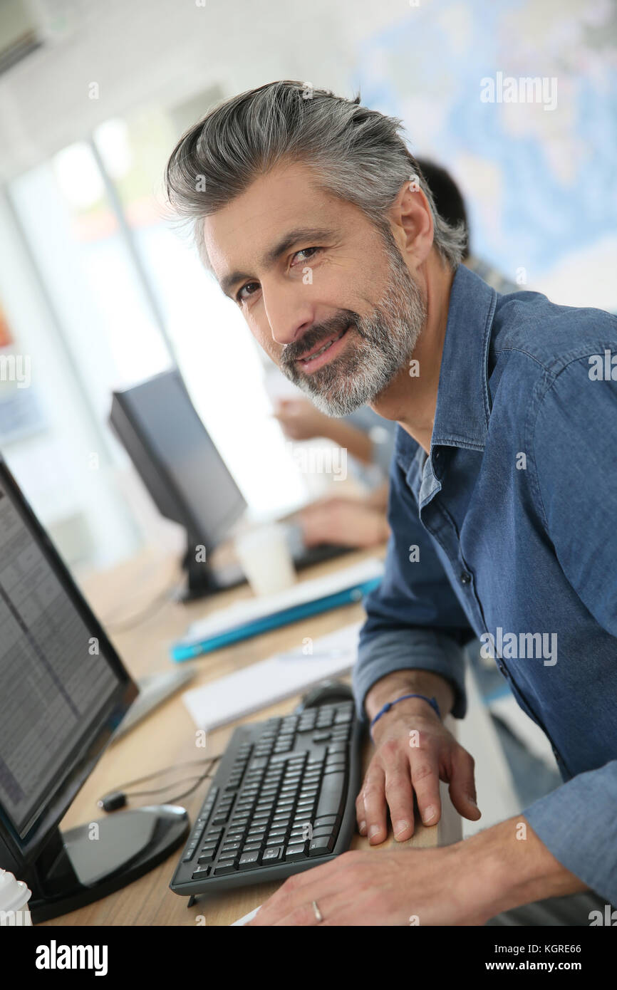 Smiling teacher working on desktop computer Stock Photo - Alamy