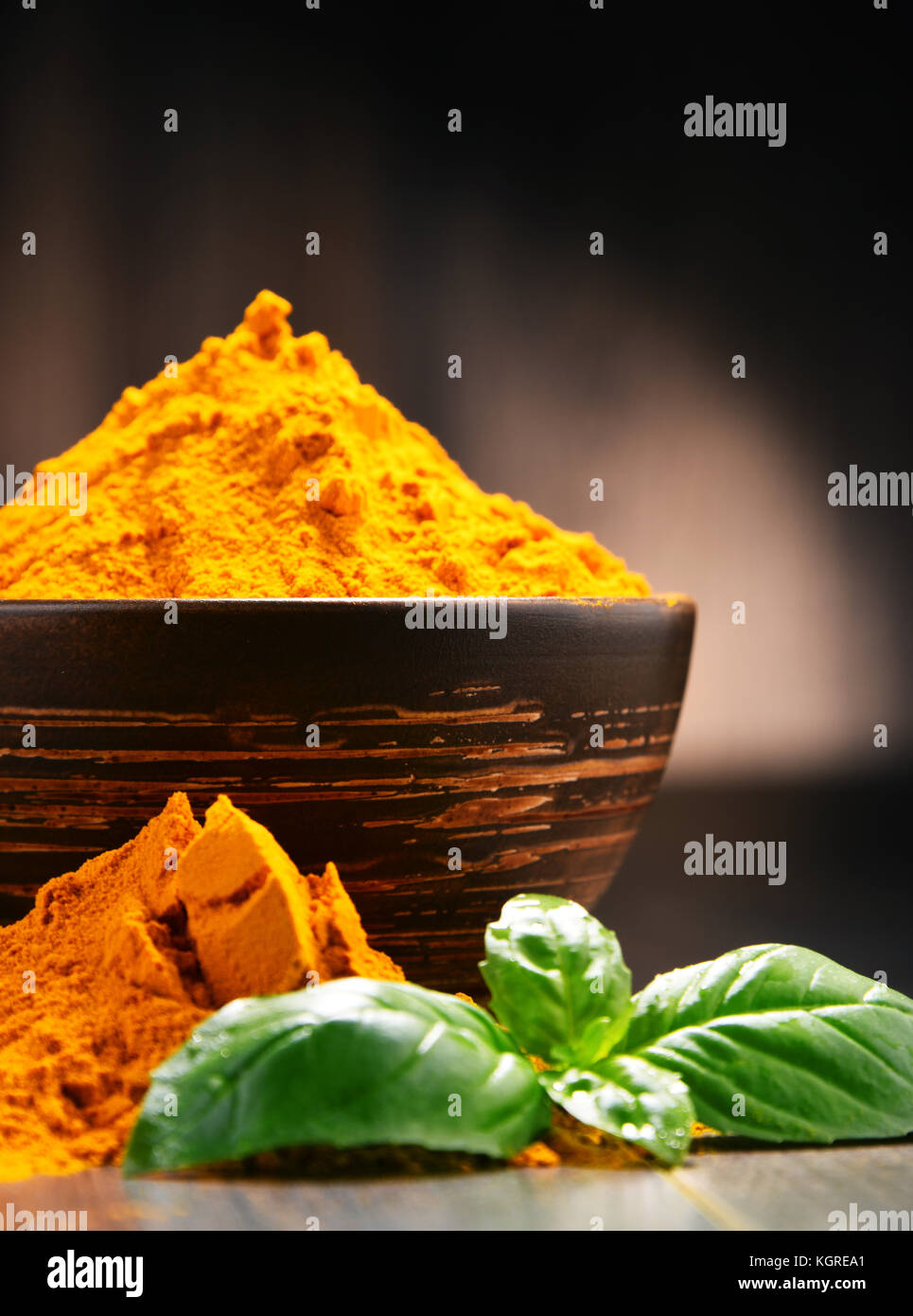 Composition with bowl of turmeric powder on wooden table Stock Photo ...