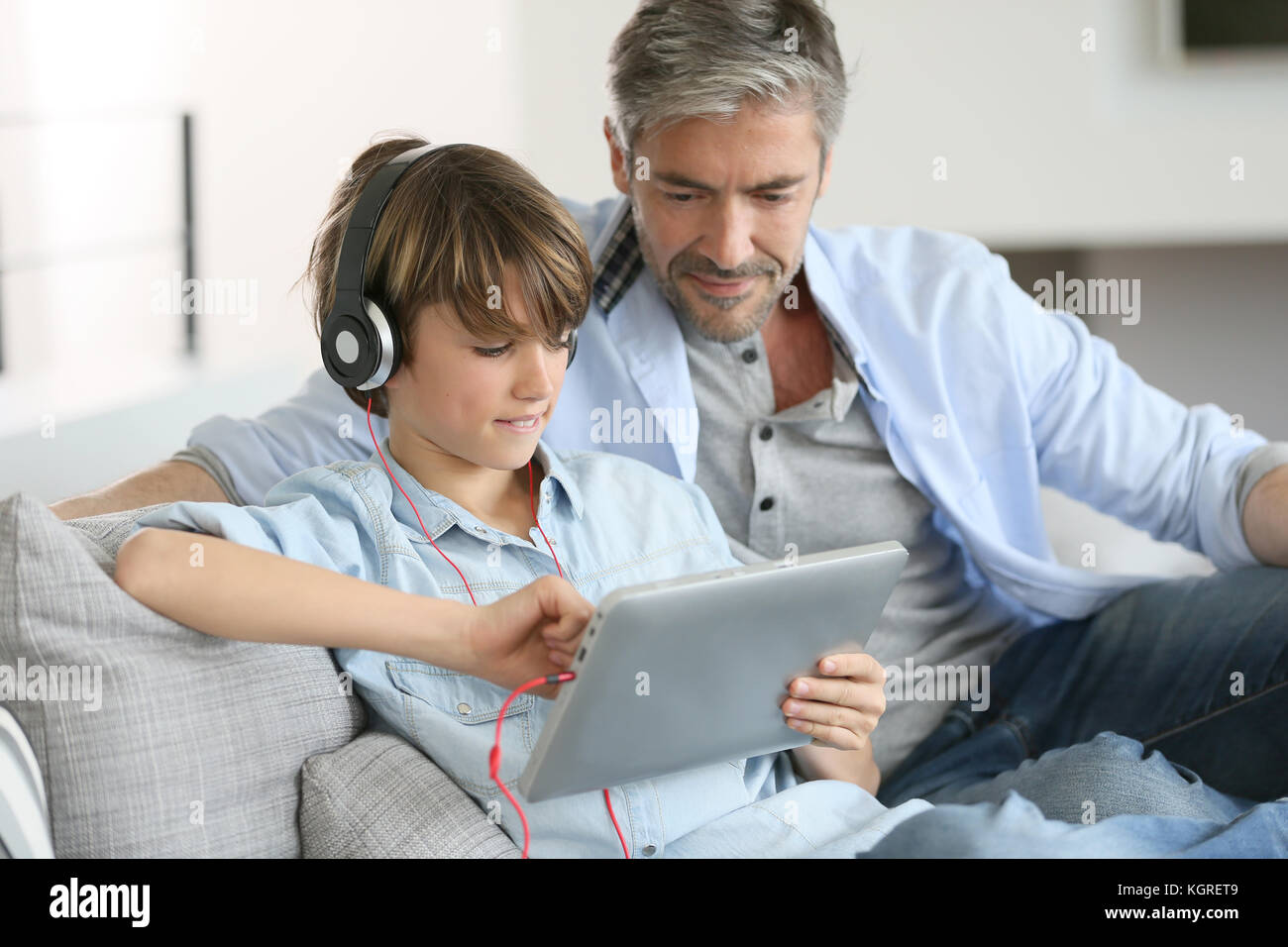 Father watching kid playing with tablet Stock Photo - Alamy