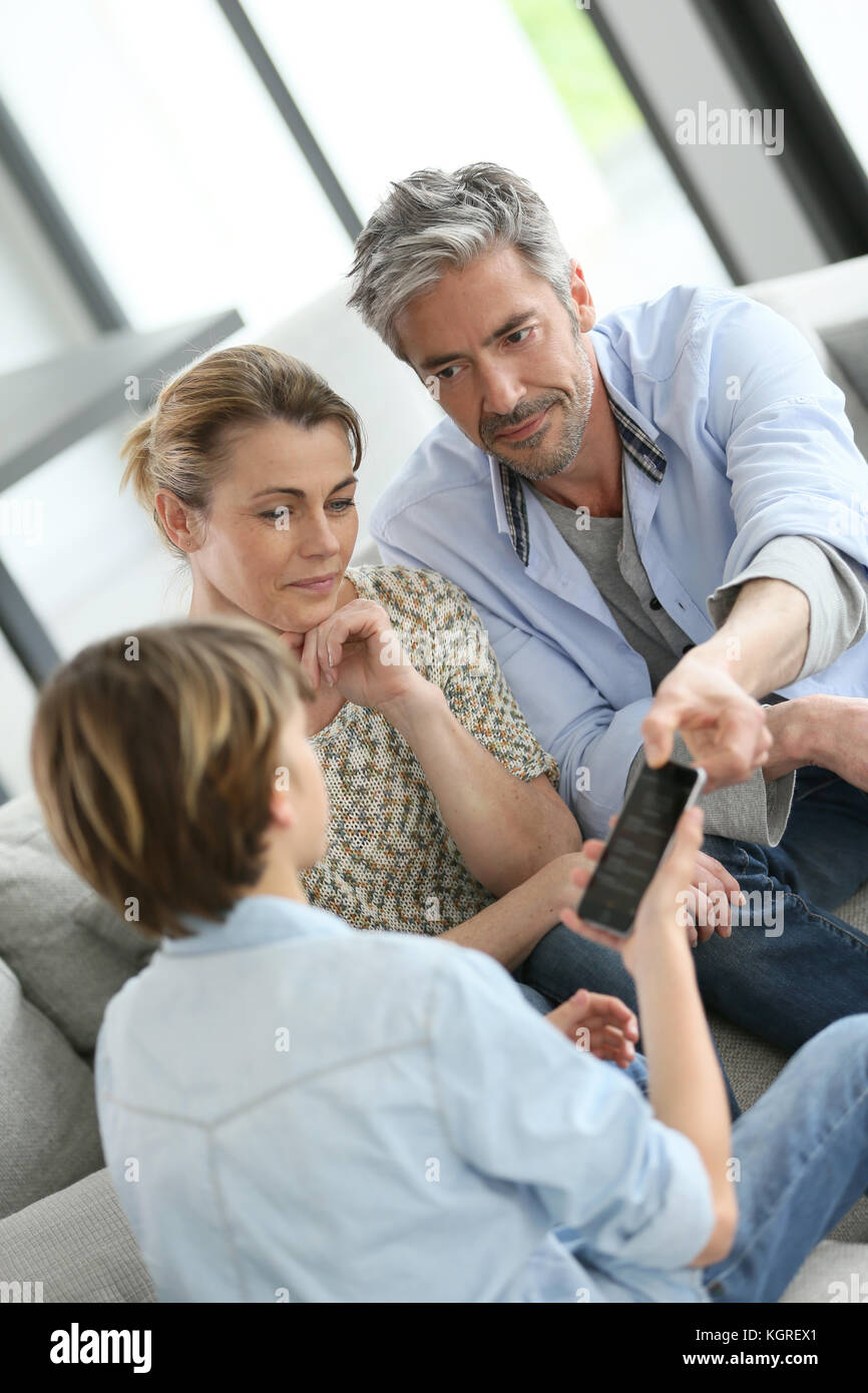 Parents giving smartphone to kid with warning Stock Photo - Alamy