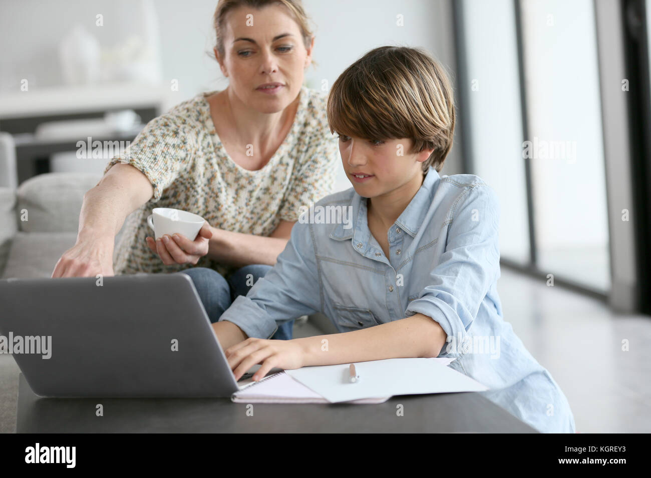 Mother looking after son doing homework on laptop Stock Photo - Alamy