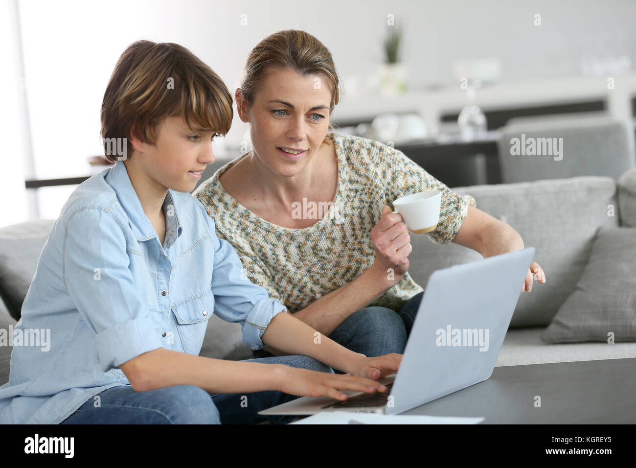 Mother looking after son doing homework on laptop Stock Photo - Alamy