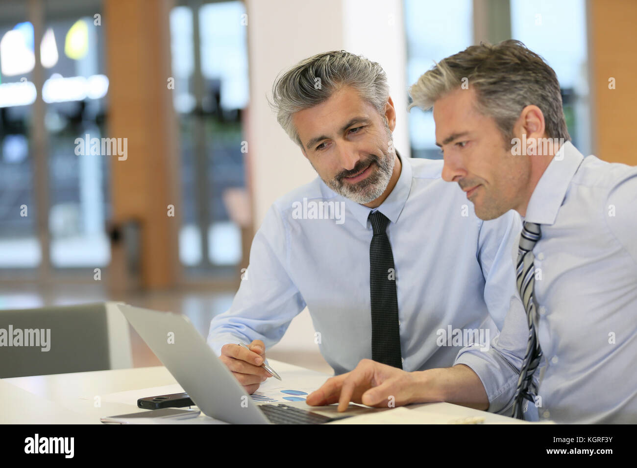 Businessmen working in office with laptop Stock Photo - Alamy