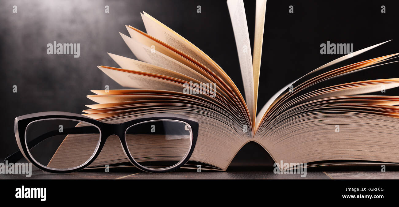 Composition with open book and glasses on the table Stock Photo - Alamy