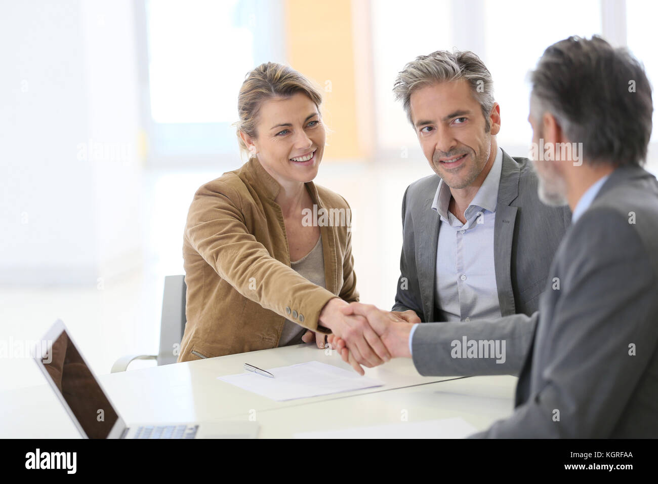 Couple in bank office shaking hand to financial adviser Stock Photo - Alamy