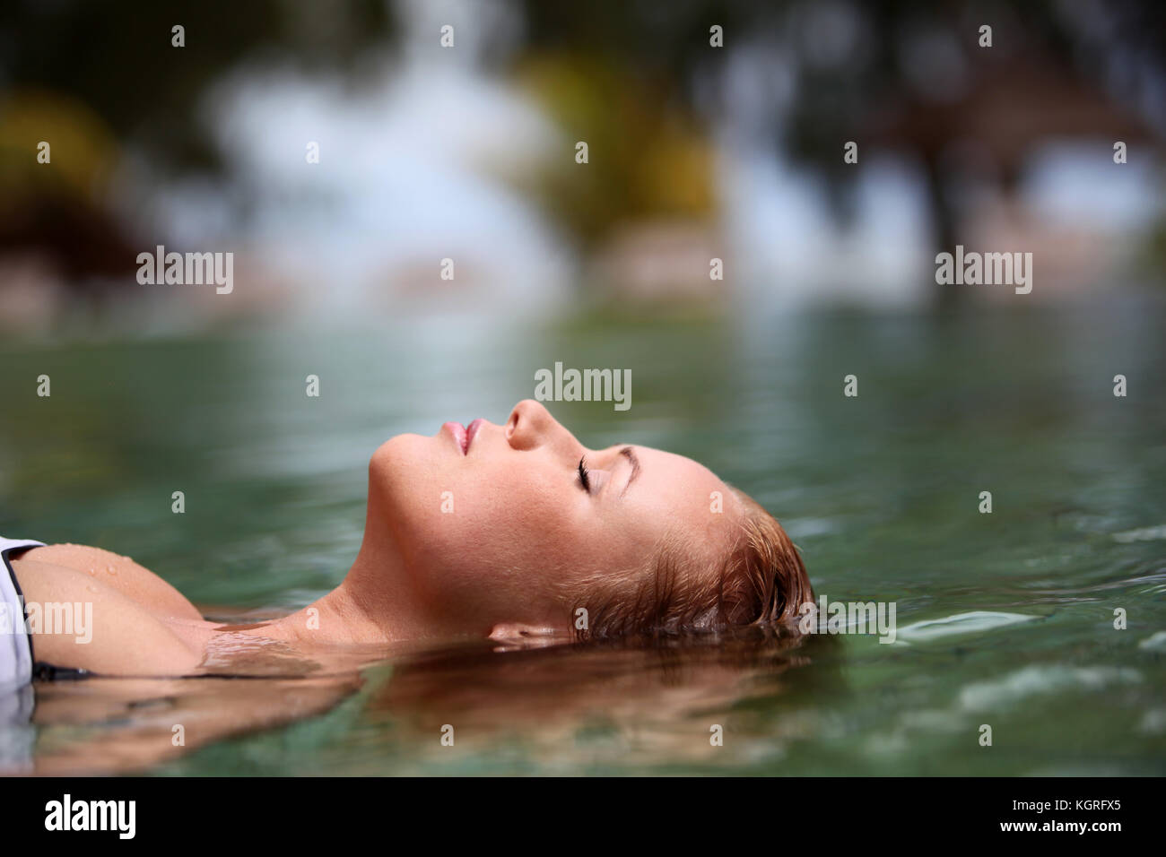 Woman floating in swimming pool Stock Photo - Alamy