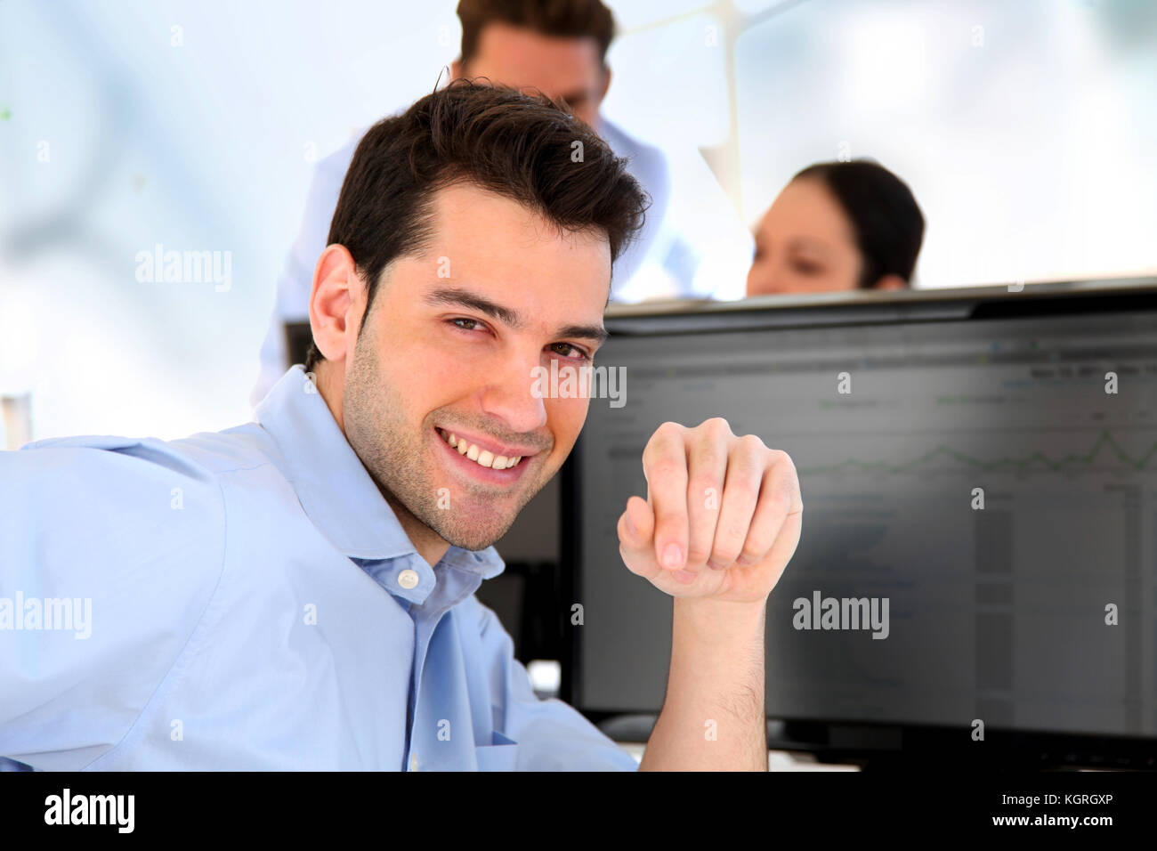 Smiling trader in front of desktop computer Stock Photo - Alamy