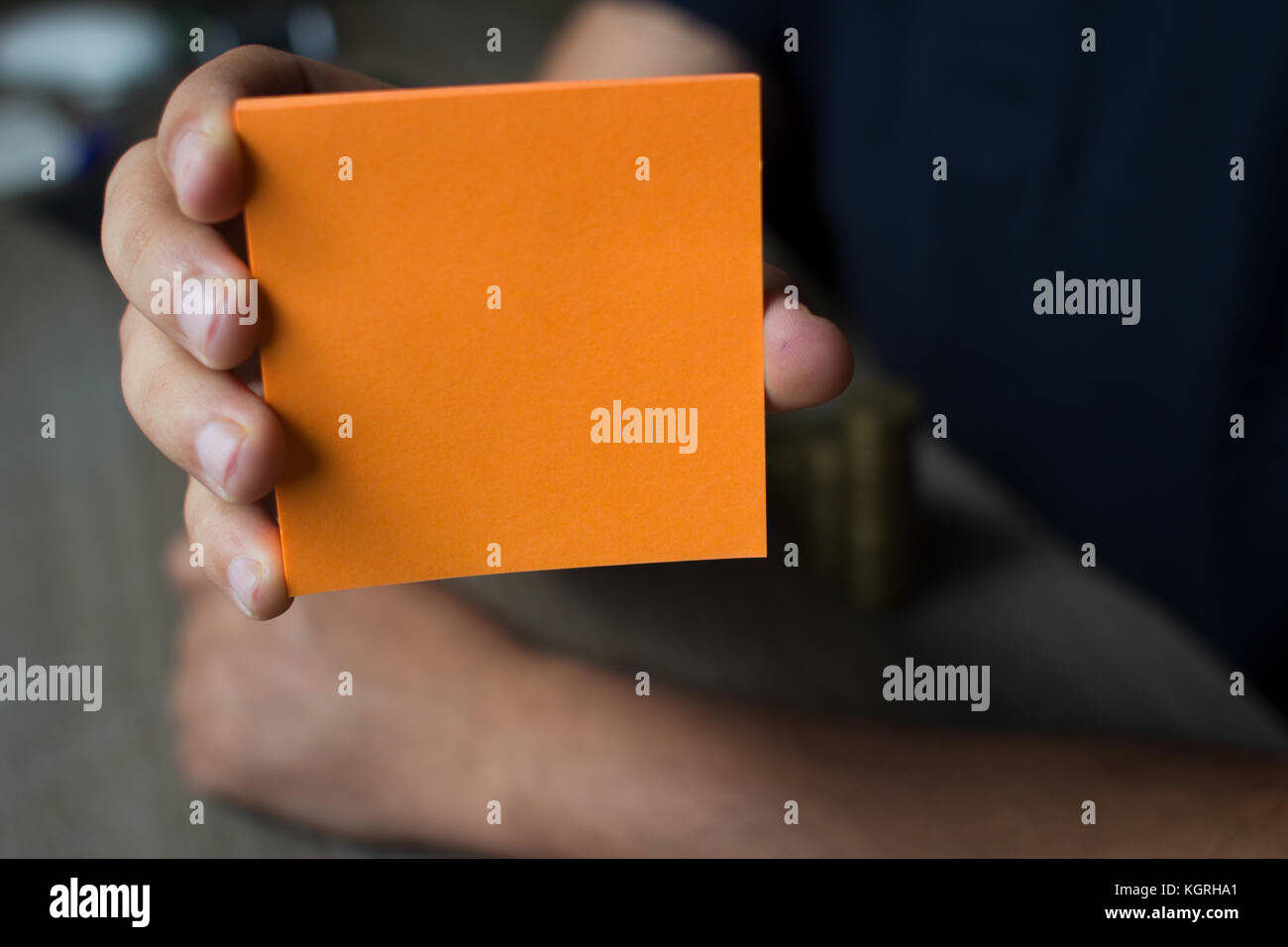 Hand holding an orange note paper - Business Concept Stock Photo - Alamy