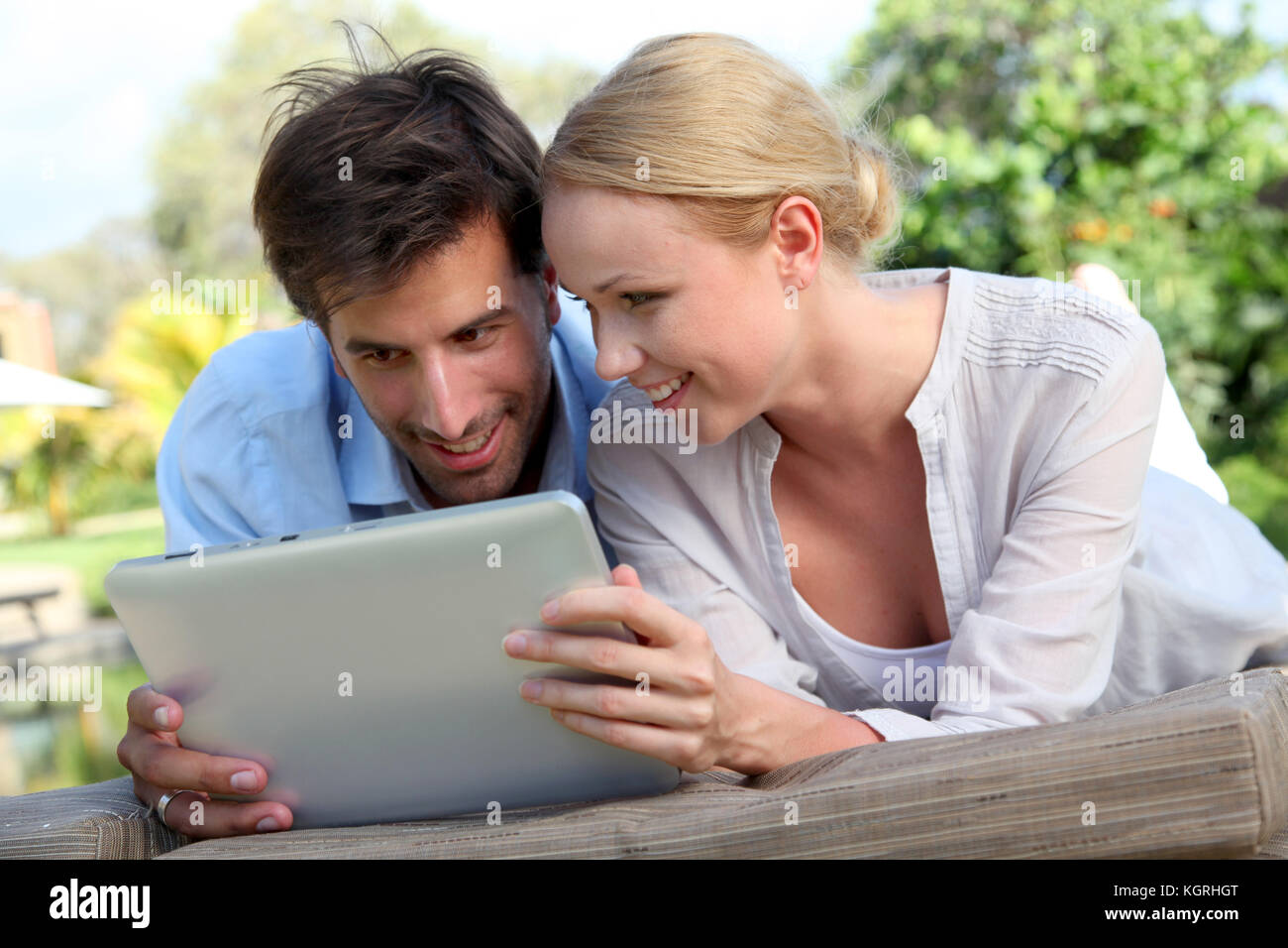Couple laying on deck chair with electronic tablet Stock Photo - Alamy