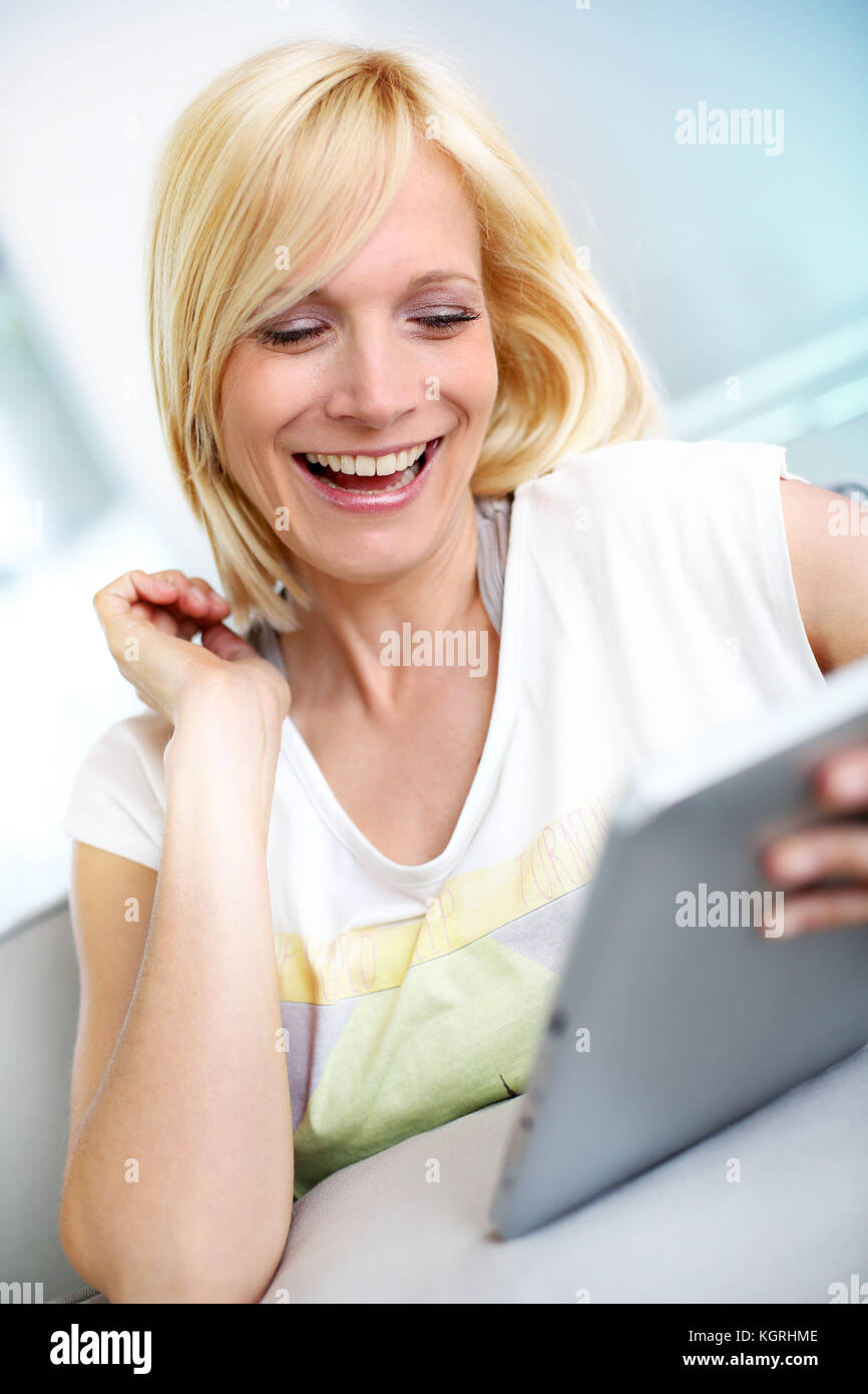 Smiling blond girl looking at tablet screen Stock Photo - Alamy