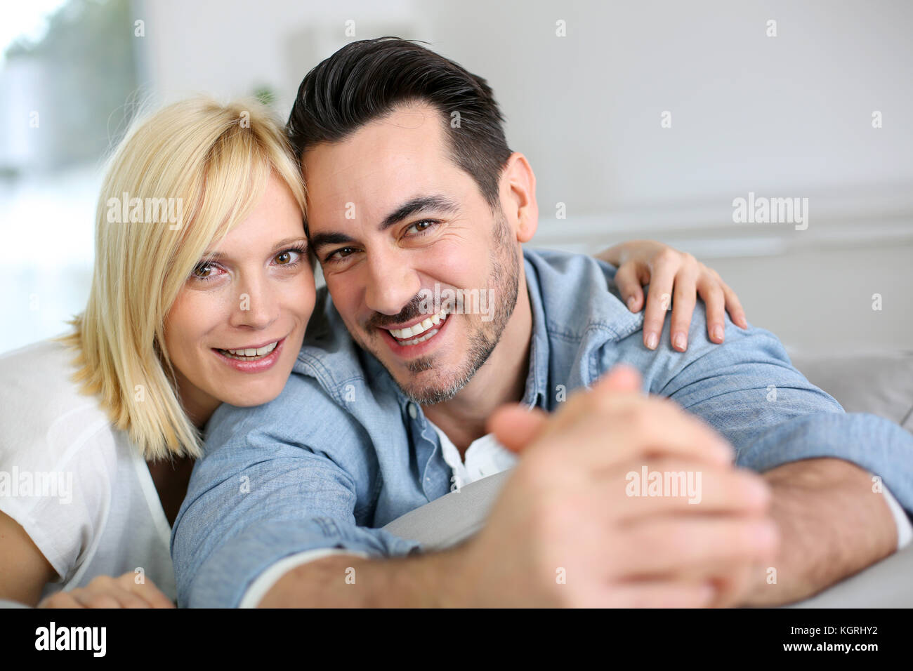 Sweet middle-aged couple embracing in sofa Stock Photo - Alamy