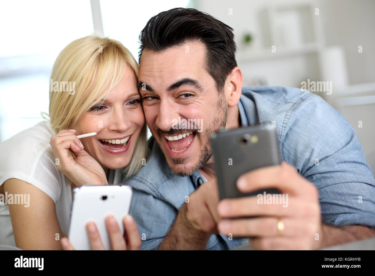 Cheerful couple having fun using smartphone Stock Photo - Alamy