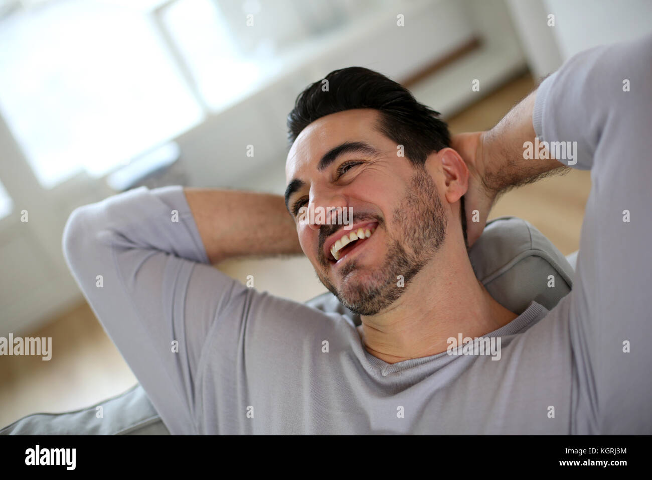 Relaxed man stretching arms behind head Stock Photo - Alamy