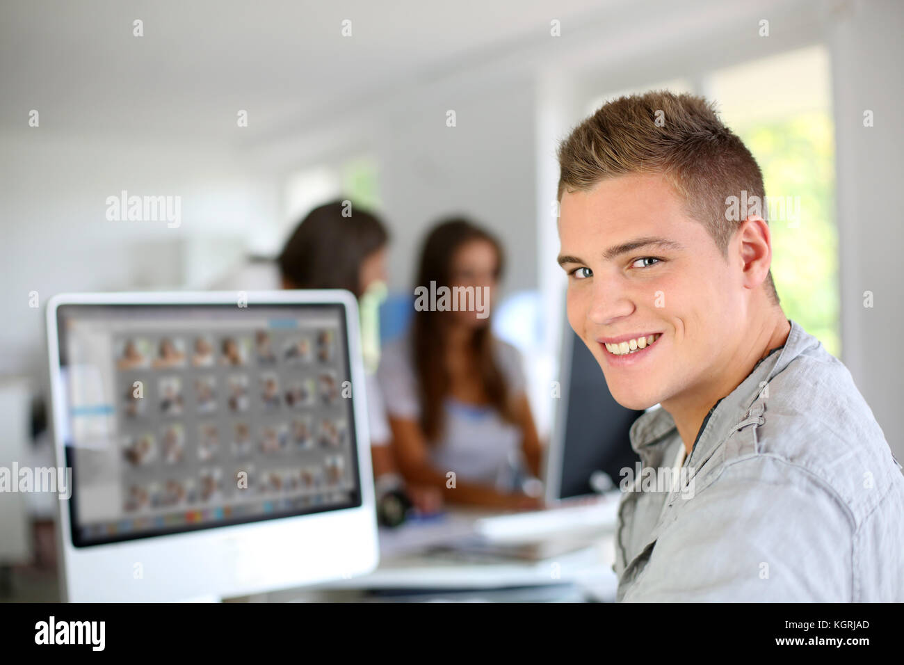 Young man sitting in office in front of desktop computer Stock Photo ...