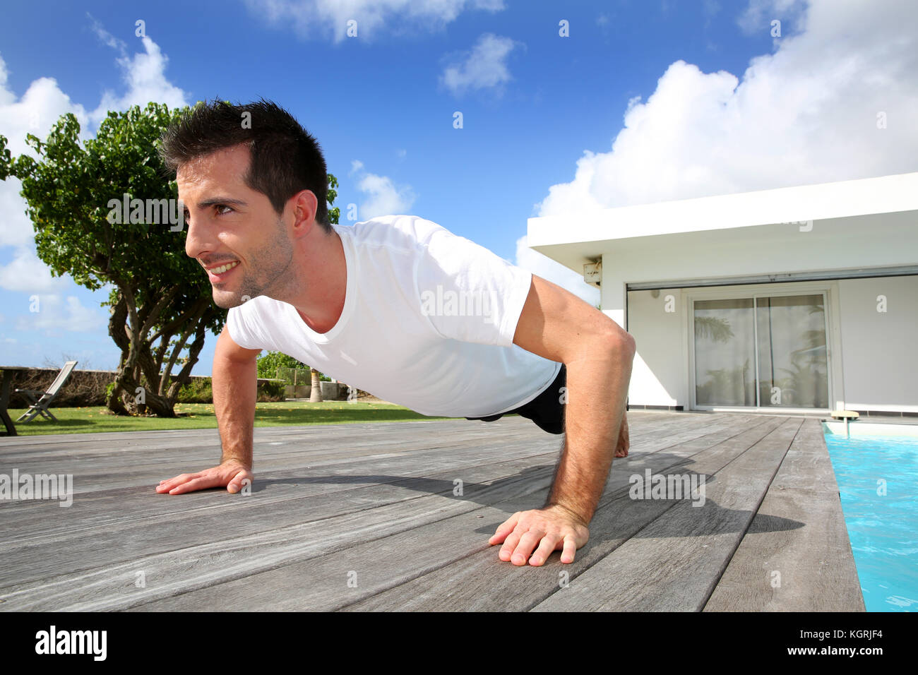 Young man doing pushups on pool deck Stock Photo - Alamy