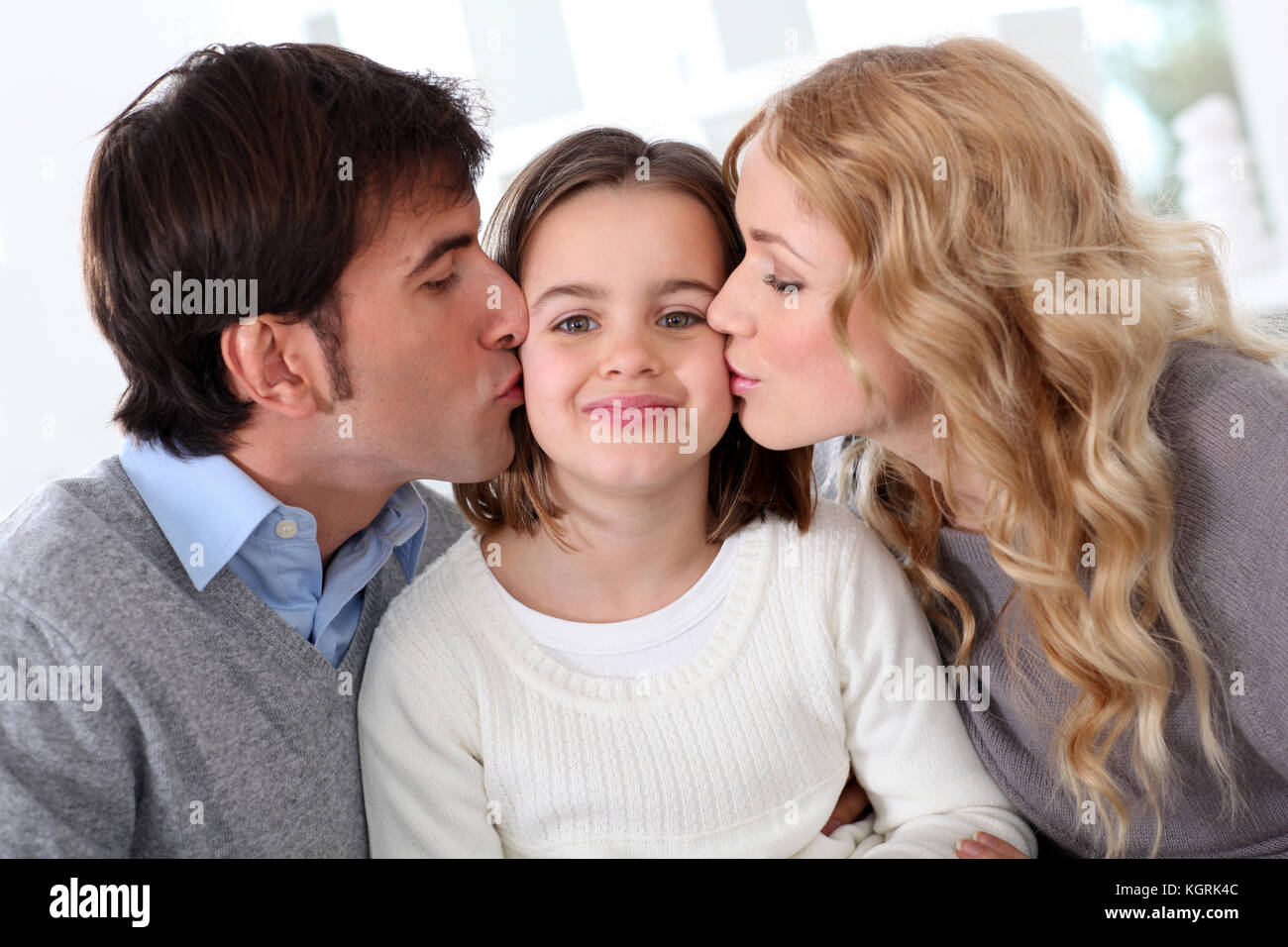 Portrait of parents kissing their daughter Stock Photo - Alamy