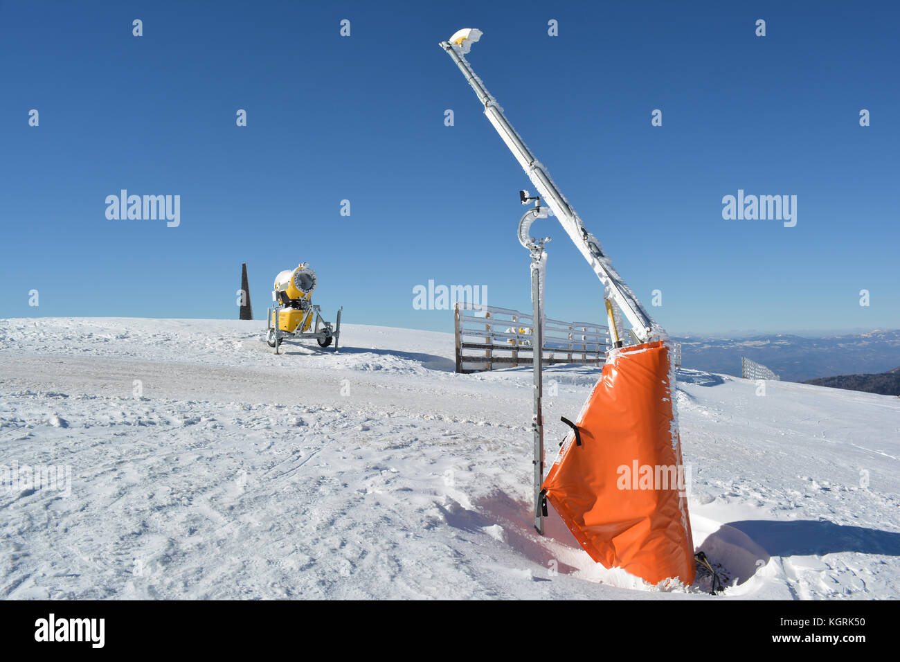 Start of the ski slopes with ramp, high wooden fence, snow cannon and ...