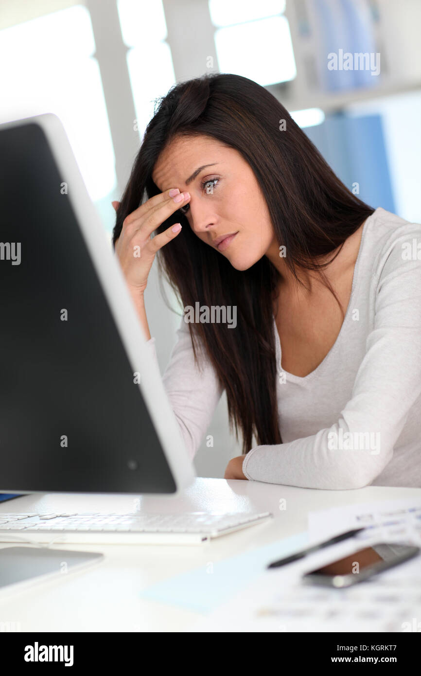 Woman in front of desktop computer having a headache Stock Photo - Alamy