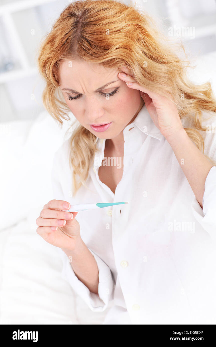 Woman with fever looking at thermometer Stock Photo - Alamy
