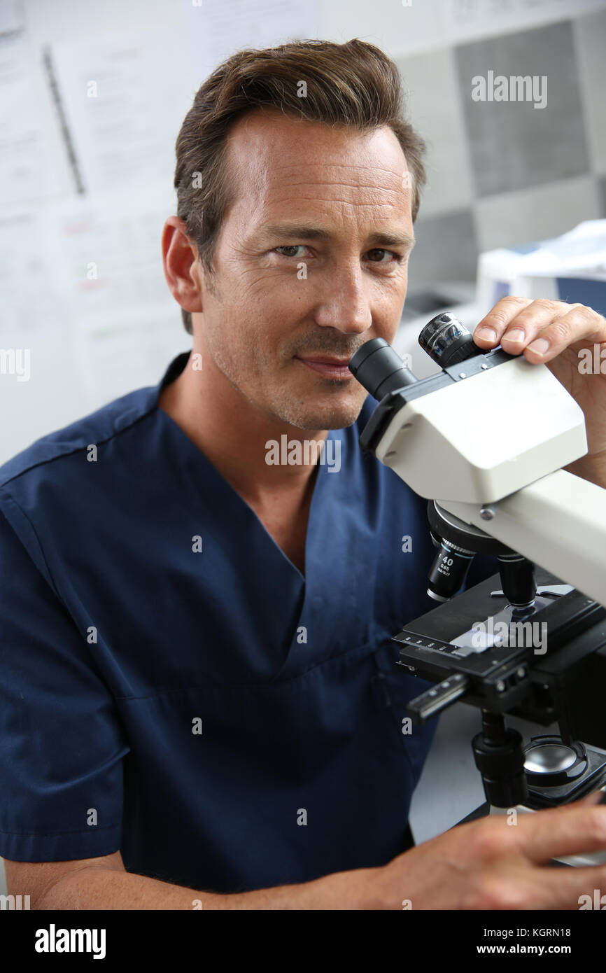 Doctor in laboratory looking through microscope Stock Photo - Alamy