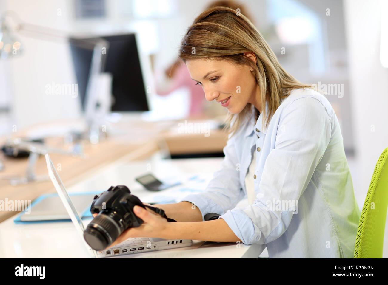Woman reporter in office looking at photo camera Stock Photo - Alamy