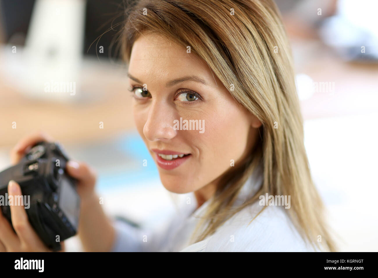 Woman reporter in office looking at photo camera Stock Photo - Alamy