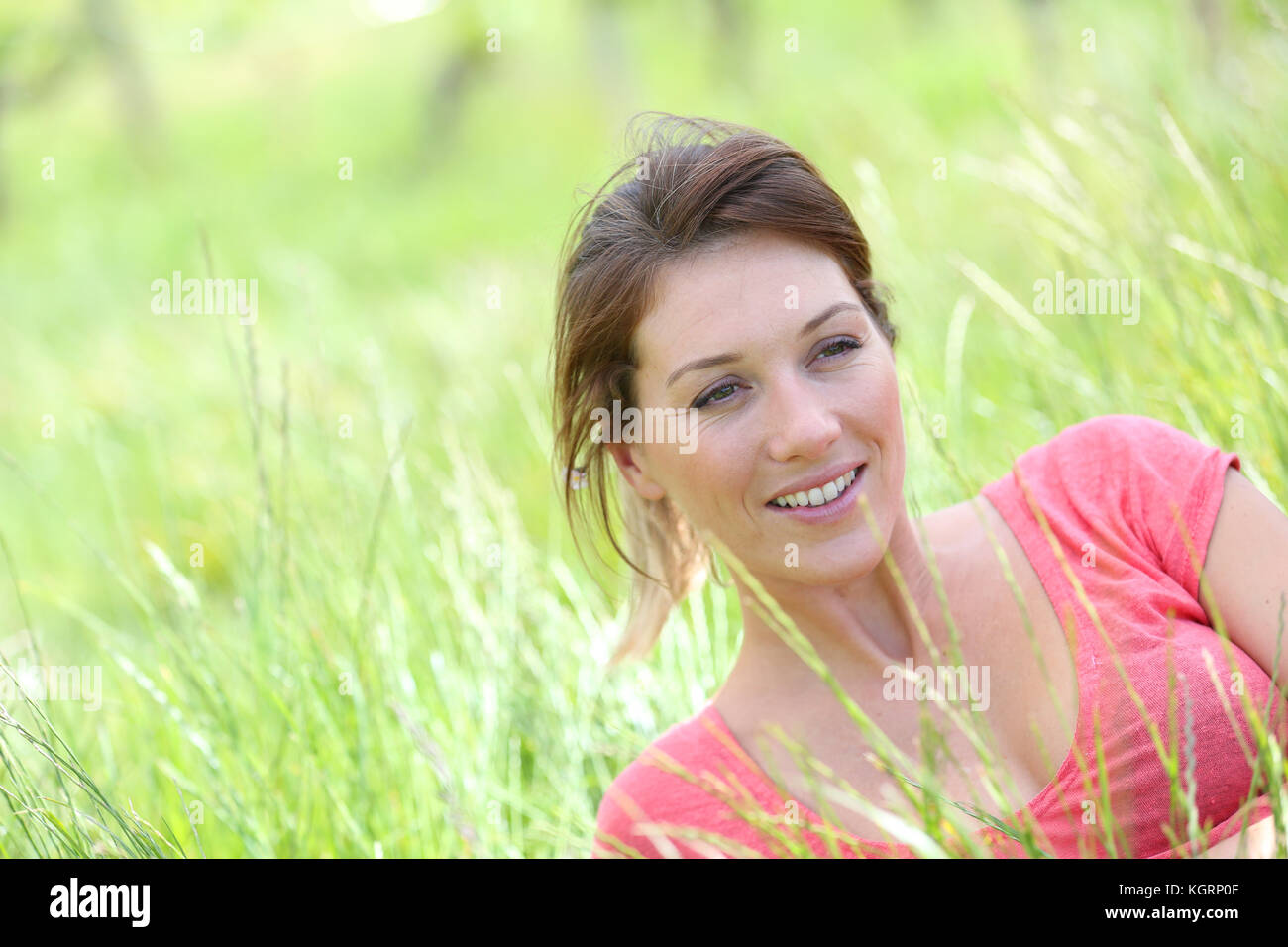 Beautiful smiling woman laying in country field Stock Photo - Alamy