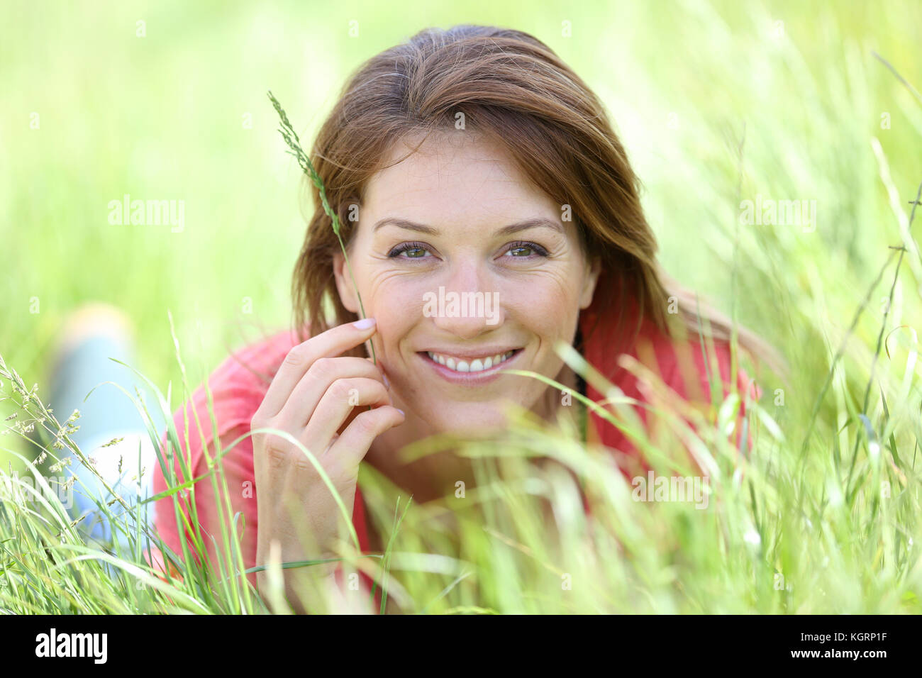 Beautiful smiling woman laying in country field Stock Photo - Alamy
